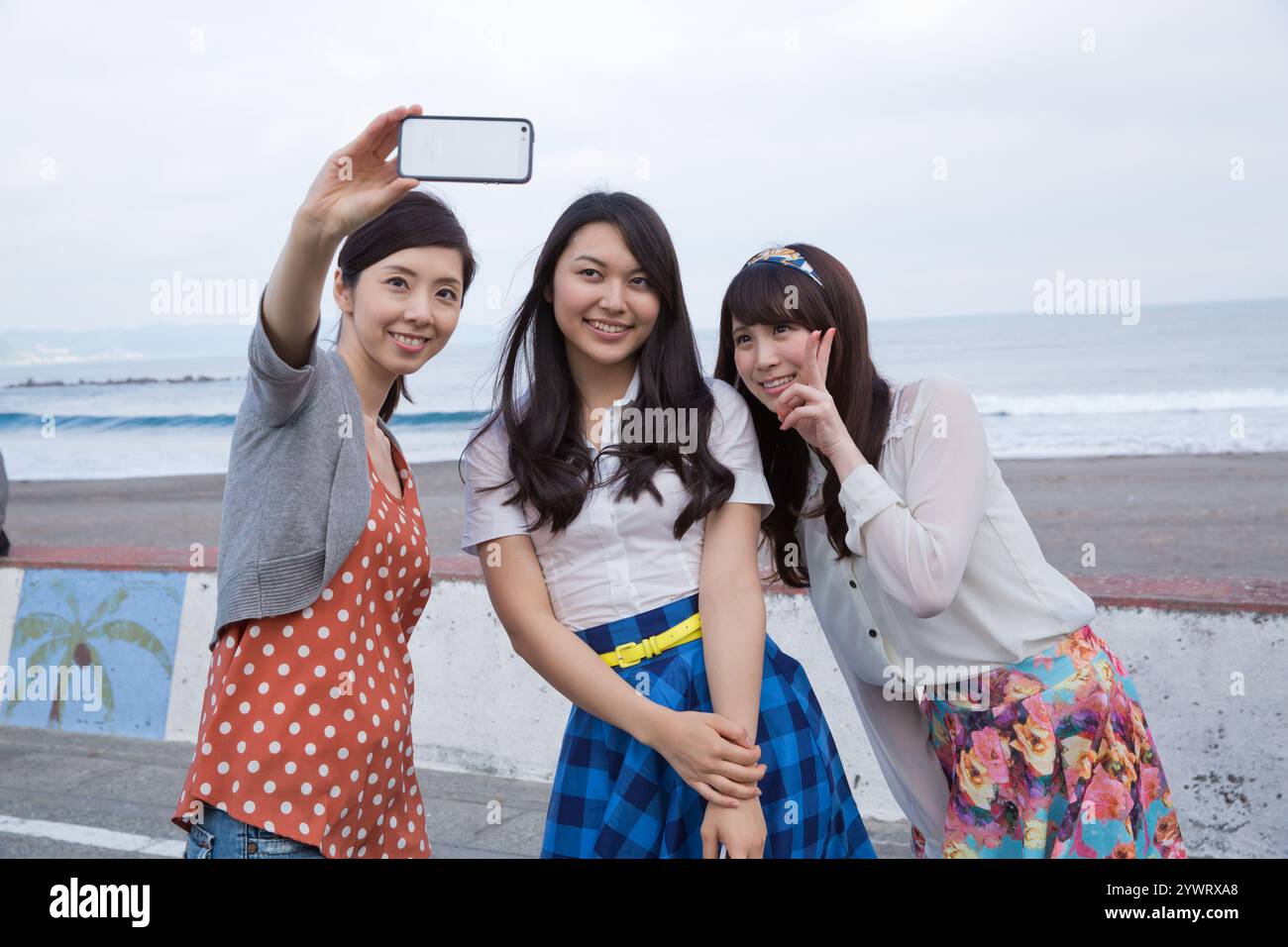 Three young women taking photos with their phones on the beach Stock ...
