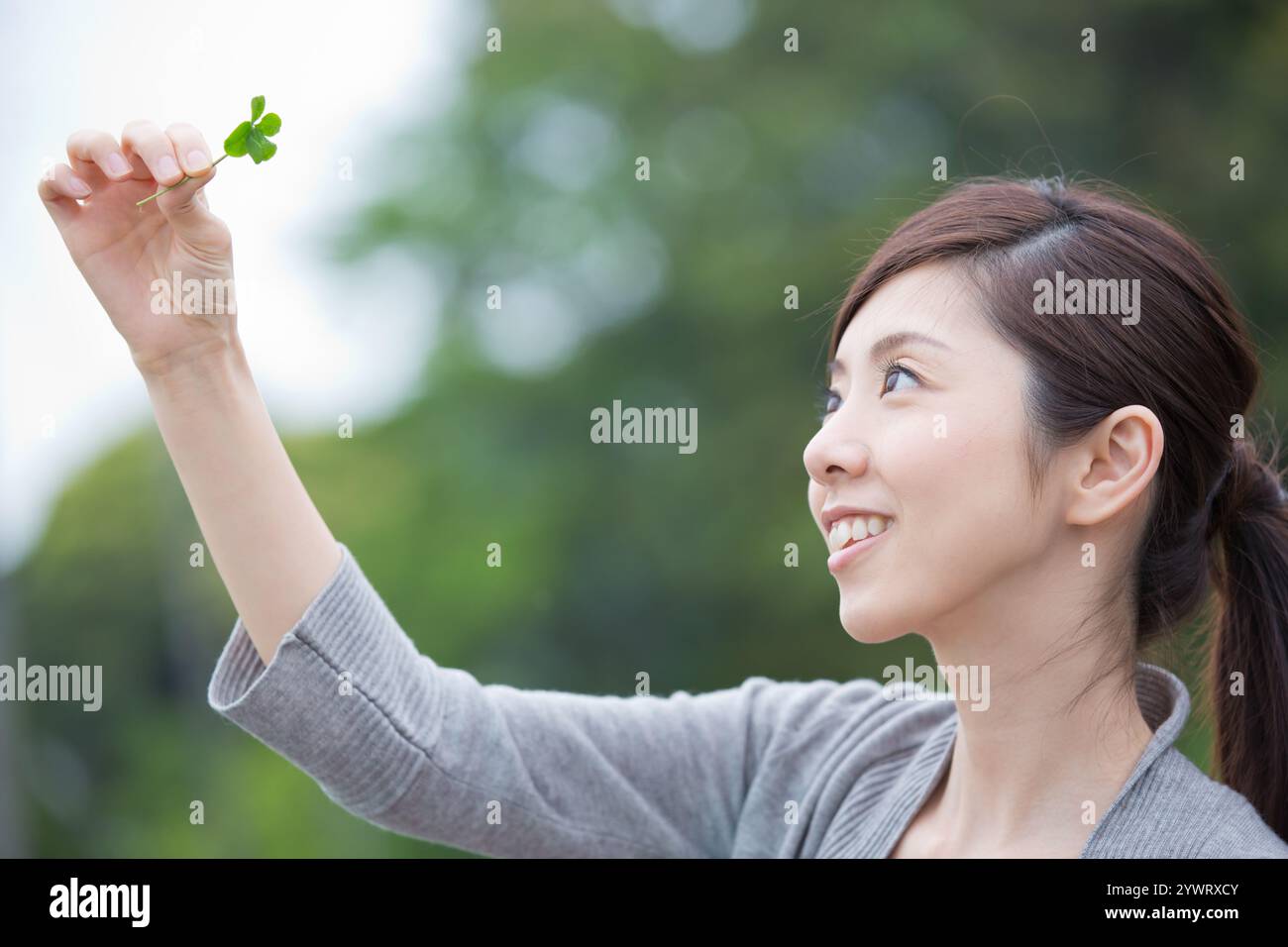 Young woman holding four-leaf clover Stock Photo - Alamy