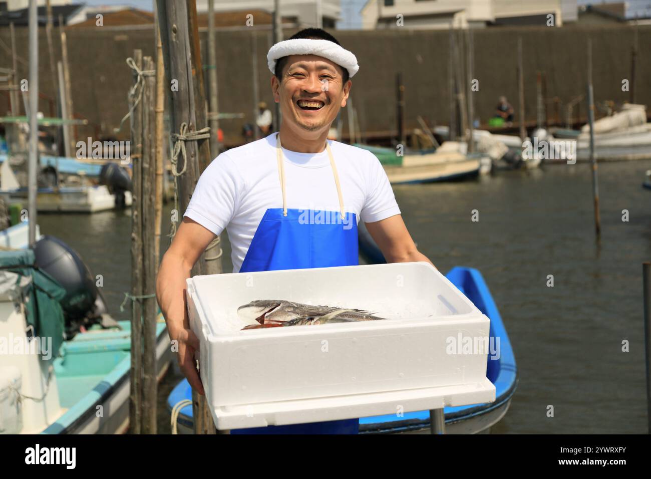 Fresh fish shopkeeper carrying a box of fish at the harbour Stock Photo ...