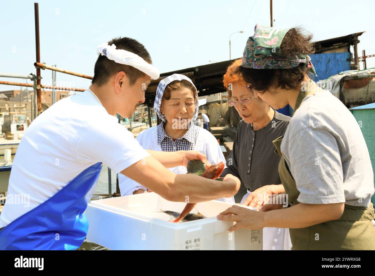 Fresh fish shopkeeper selling fish outdoors with female customers Stock ...