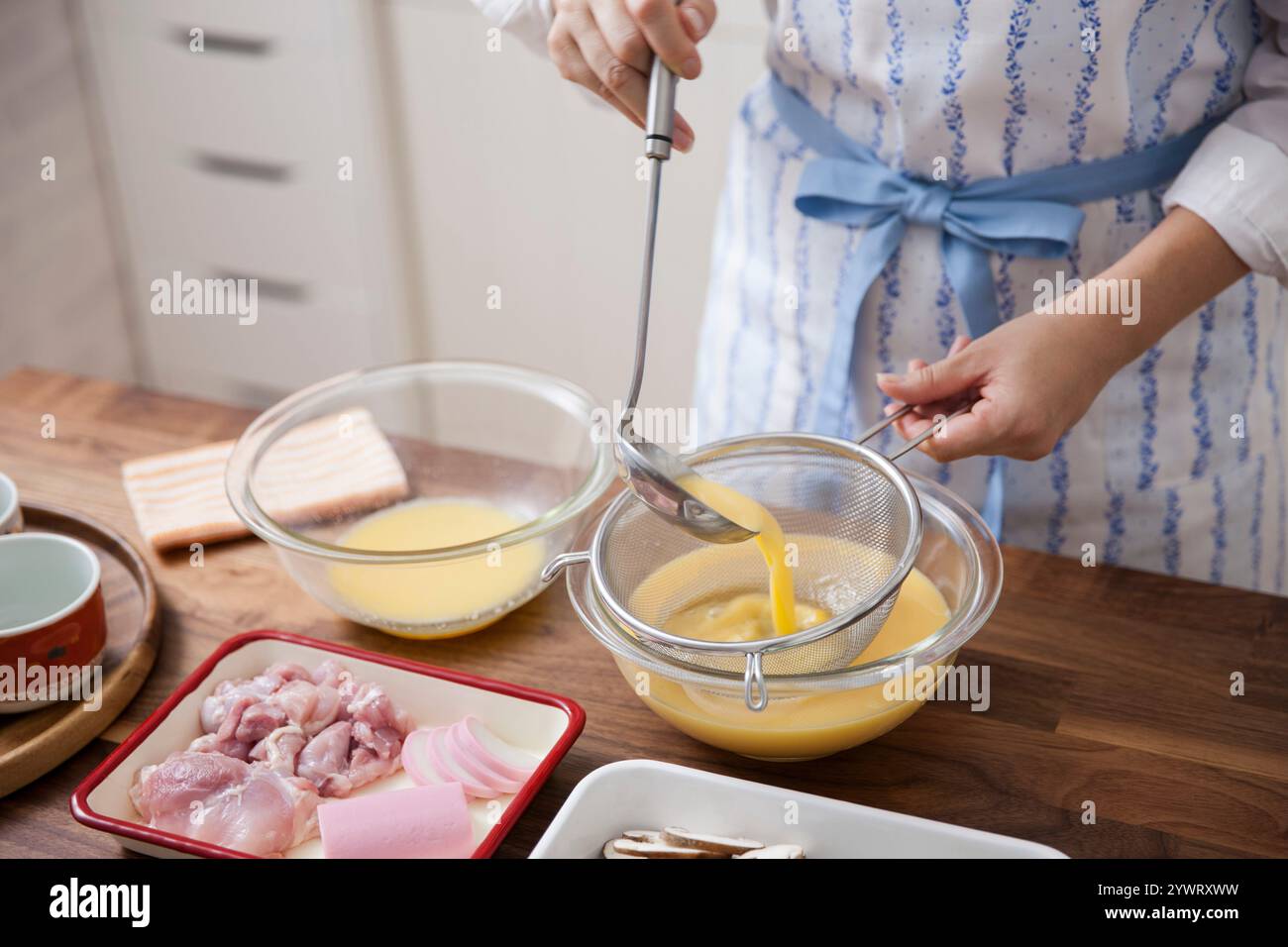 Woman straining egg liquid with broth Stock Photo - Alamy