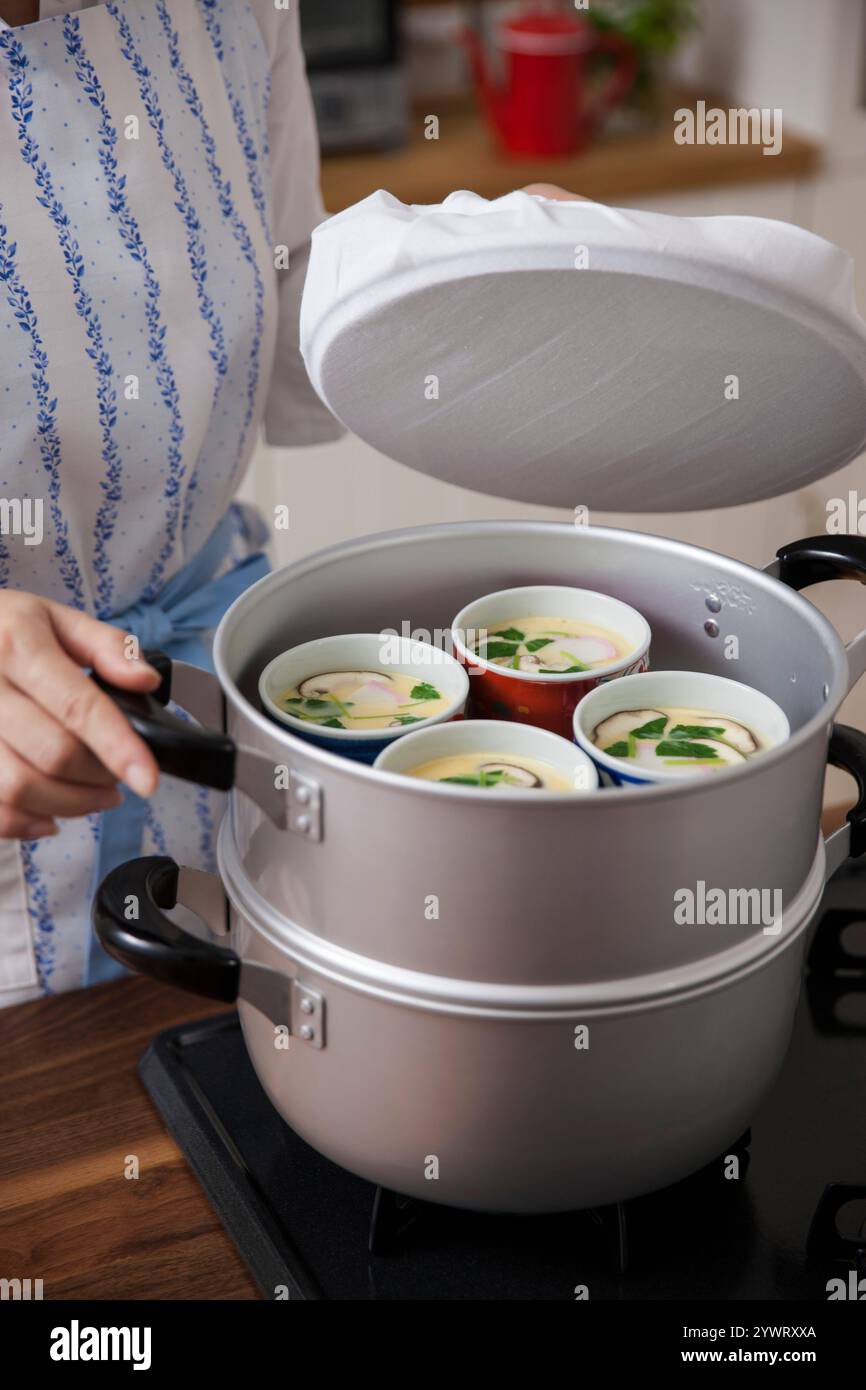 Woman putting a lid on a steamer containing steamed egg custard Stock ...