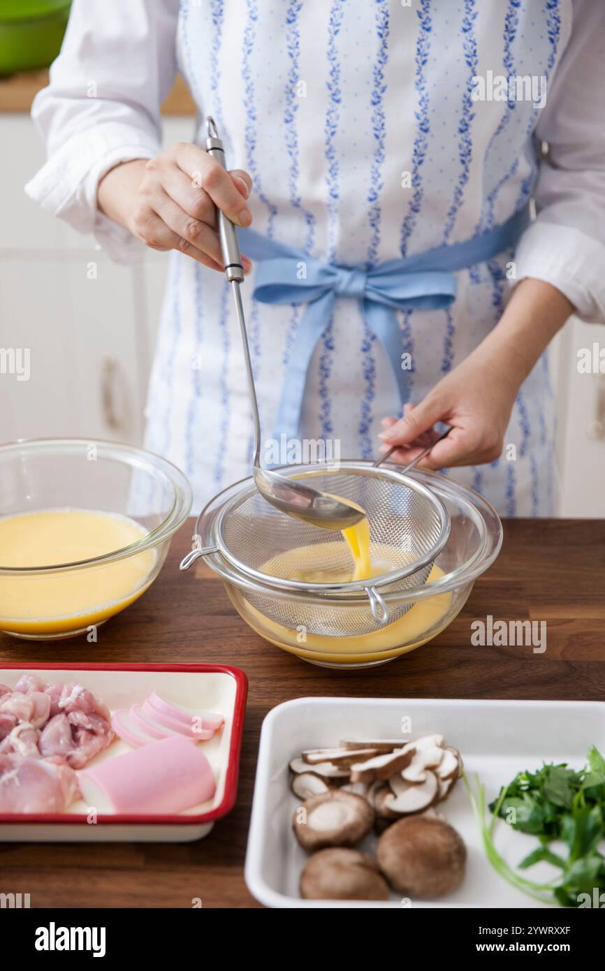 Woman straining egg liquid with broth Stock Photo - Alamy