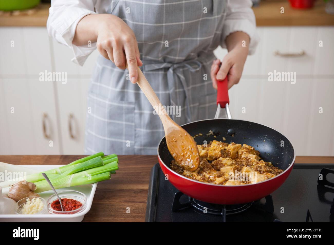 Woman stir-frying minced meat, tofu and seasoning Stock Photo - Alamy