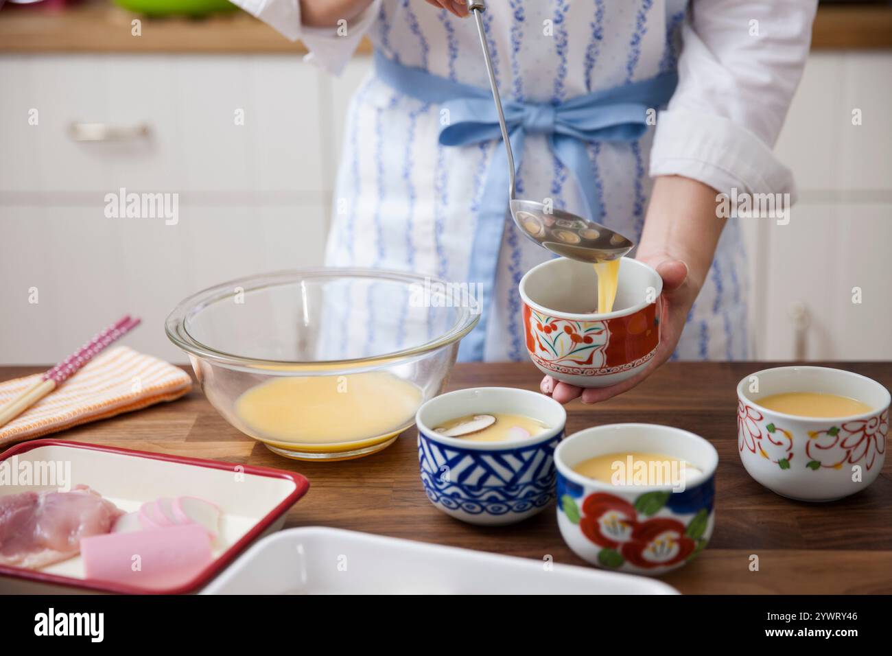 Woman pouring the egg mixture into the steamed egg custard container ...