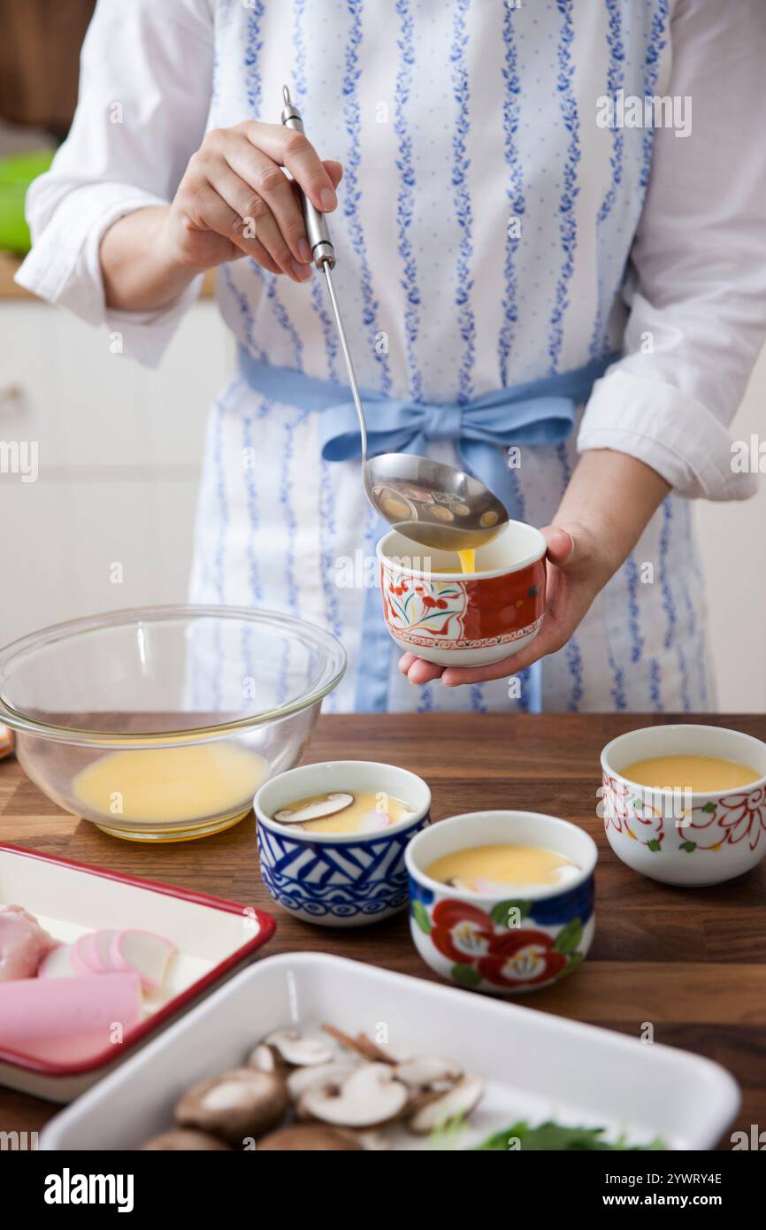 Woman pouring the egg mixture into the steamed egg custard container ...