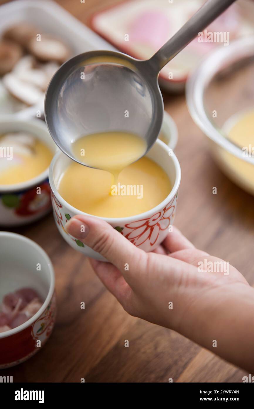 Woman pouring the egg mixture into the steamed egg custard container ...