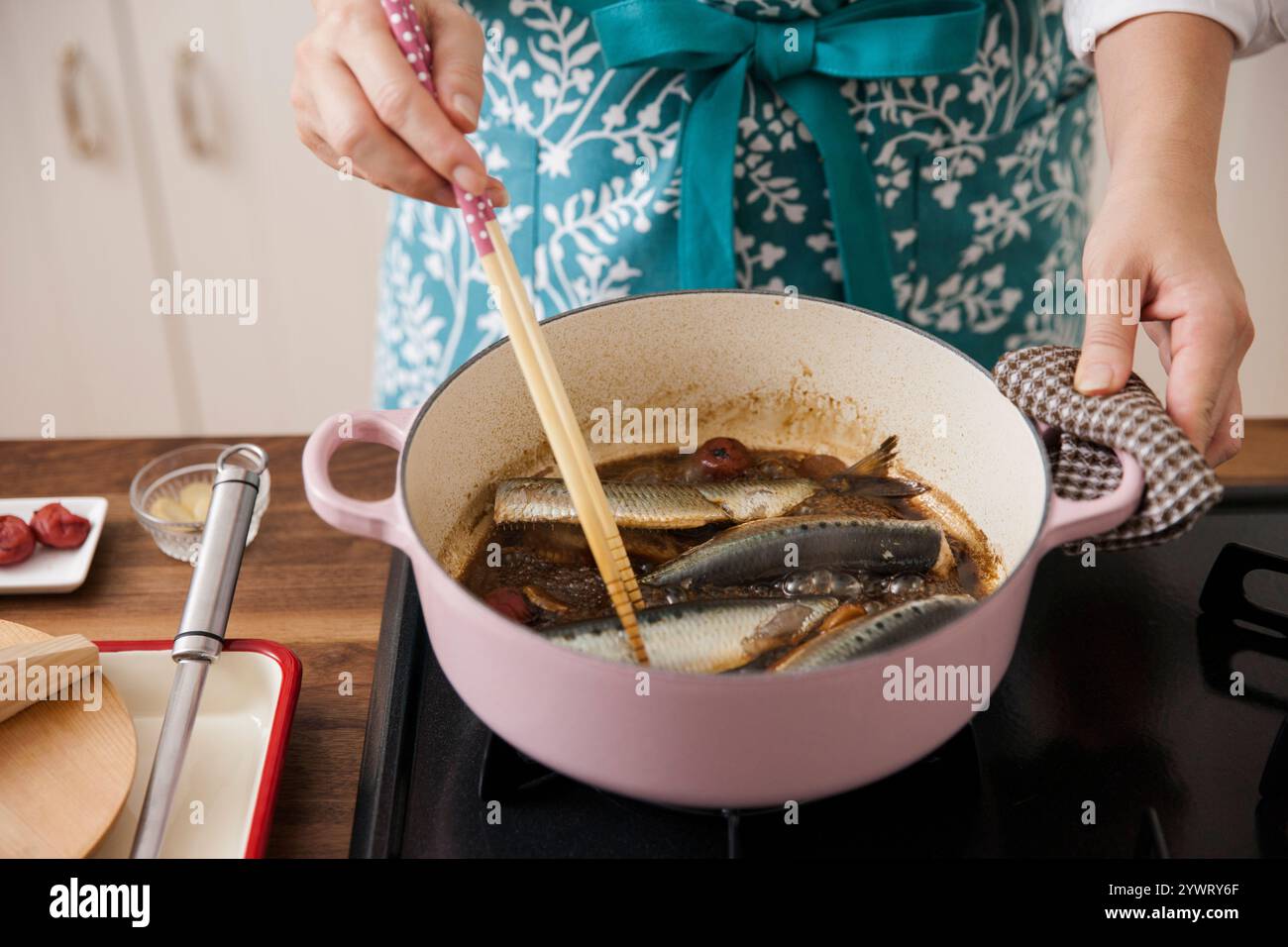 Woman boiling sardines in pickled plums and broth Stock Photo - Alamy