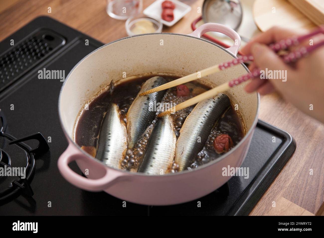 Woman boiling sardines in pickled plums and broth Stock Photo - Alamy