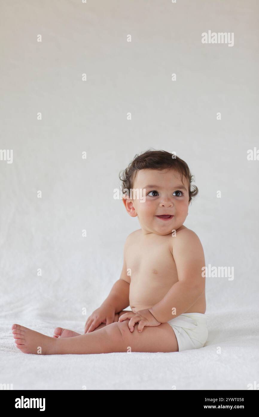Foreign baby sitting on bed Stock Photo - Alamy