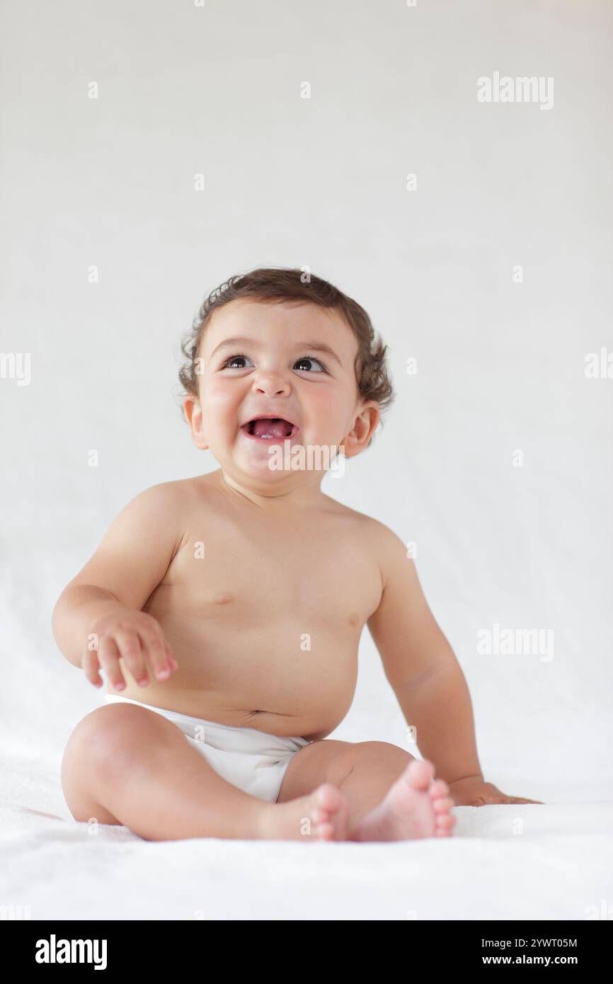Foreign baby sitting on bed Stock Photo - Alamy