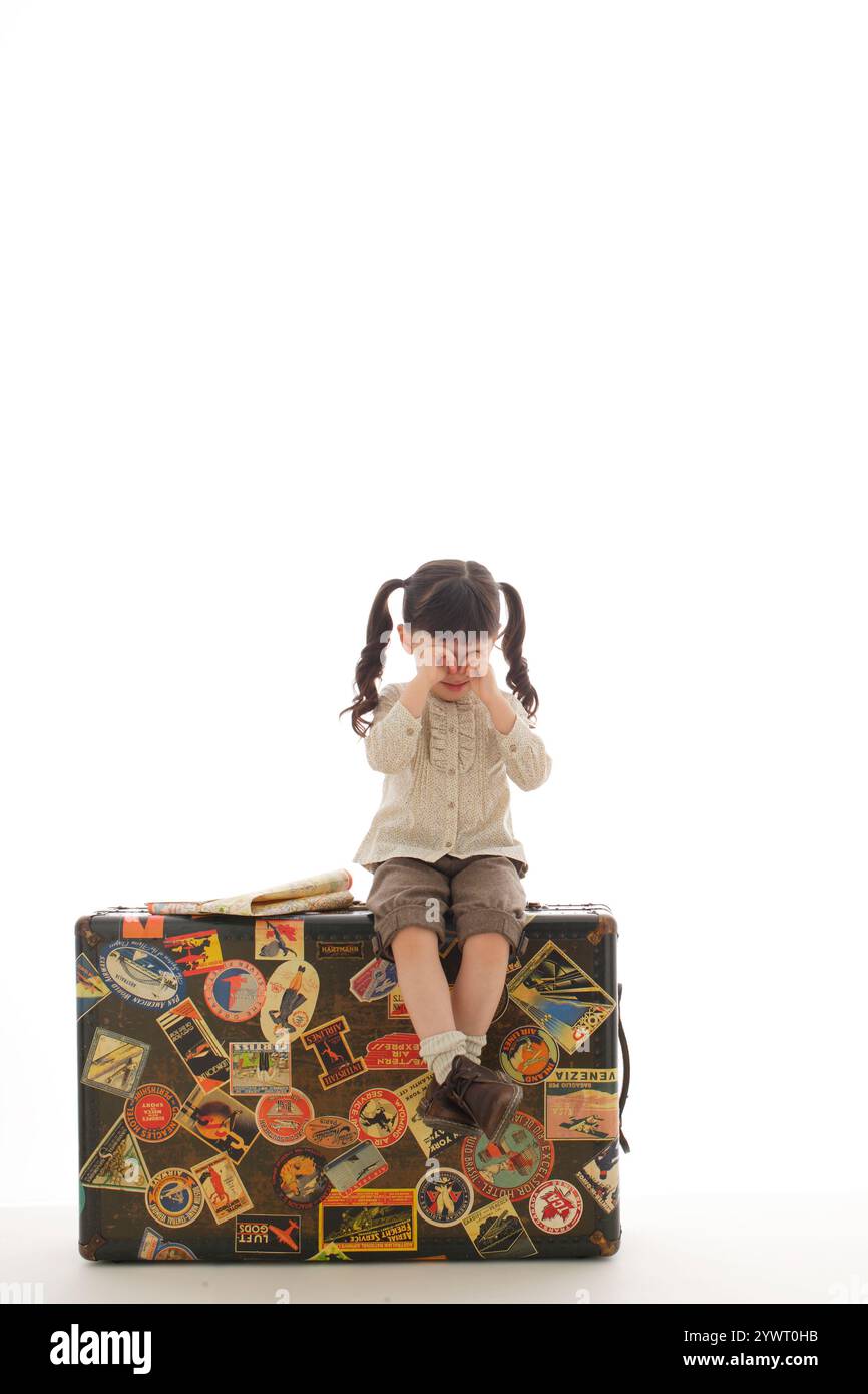 Lost girl sitting in suitcase and crying Stock Photo - Alamy
