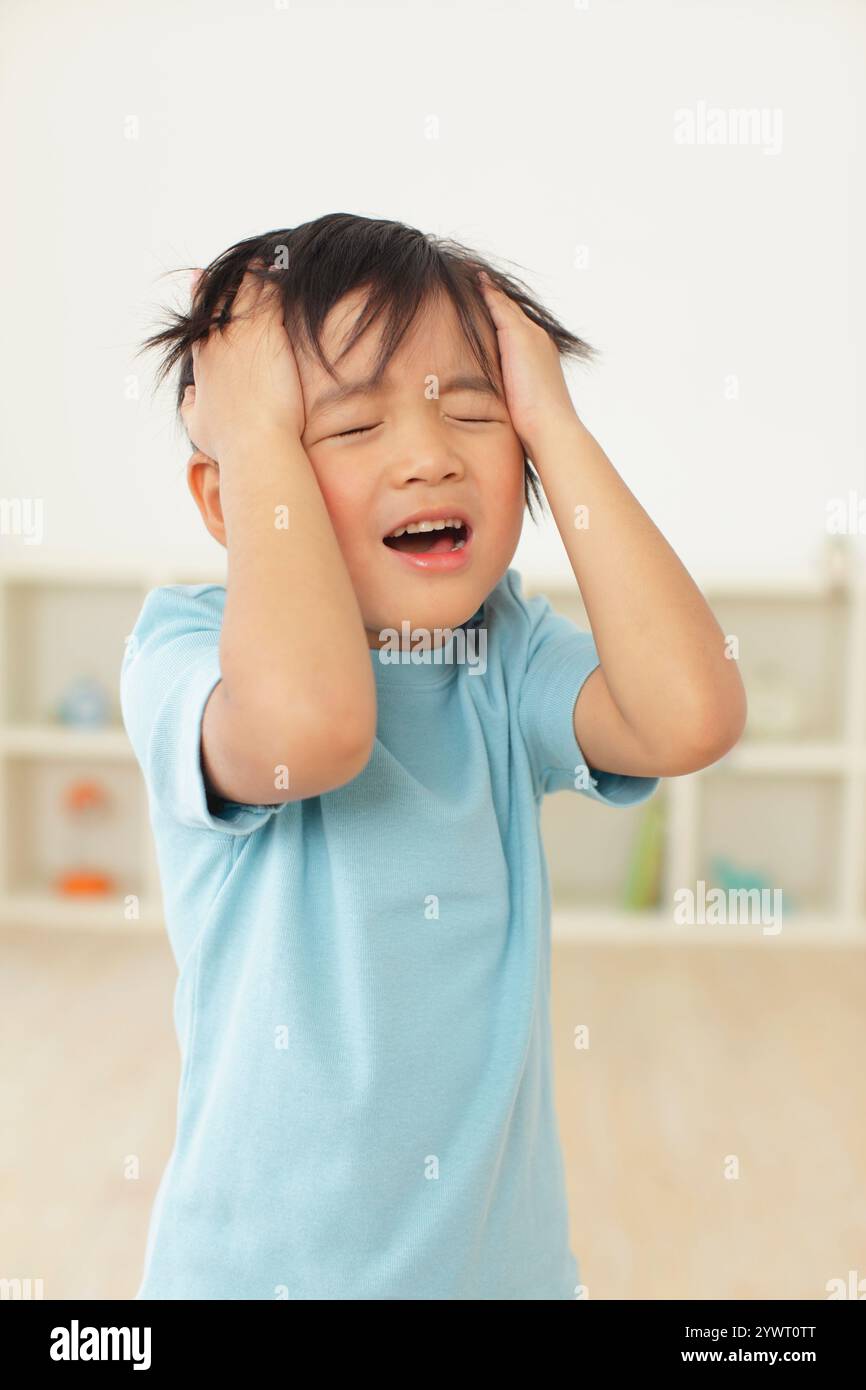 Boy holding head Stock Photo - Alamy