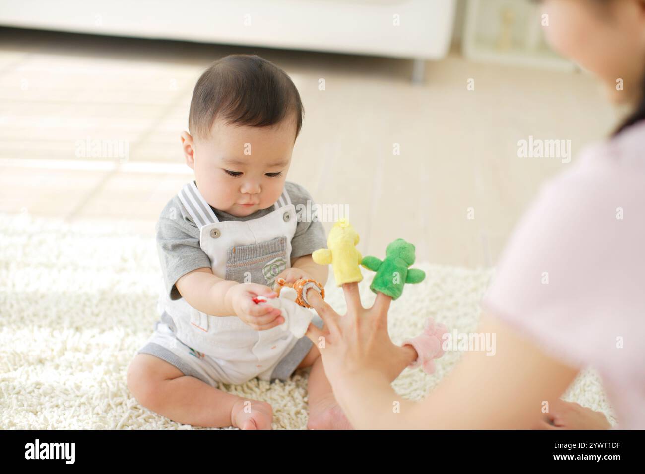 Baby and mother playing with finger puppets in living room Stock Photo ...