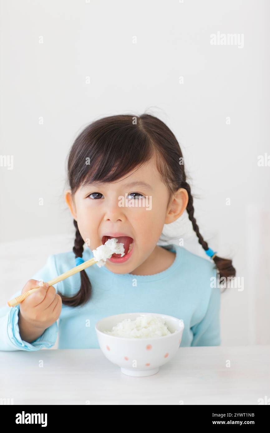 Girl eating rice Stock Photo - Alamy
