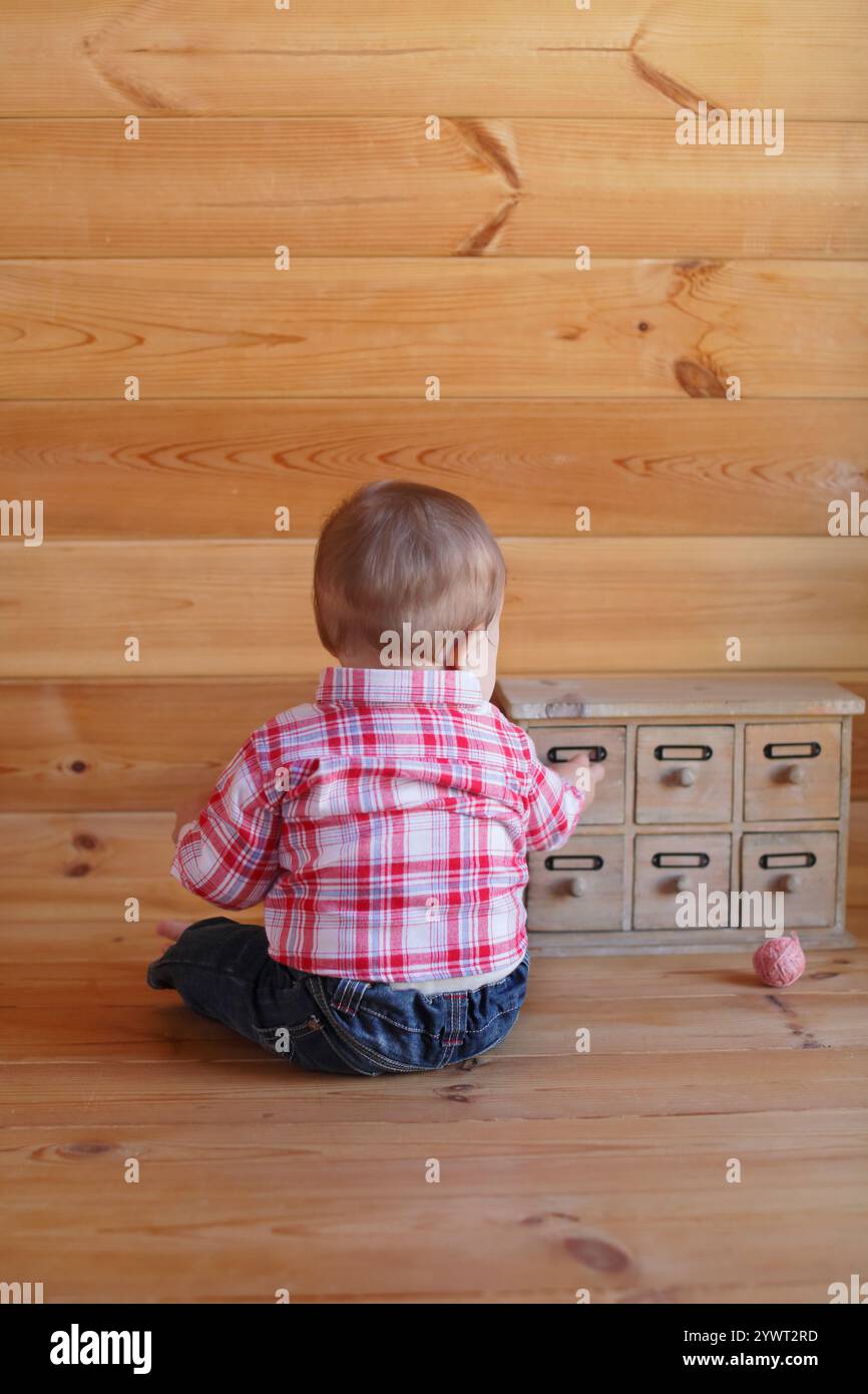Back view of baby sitting and playing on wooden floor Stock Photo - Alamy