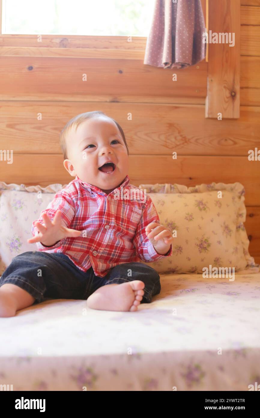 Baby sitting on bed Stock Photo - Alamy