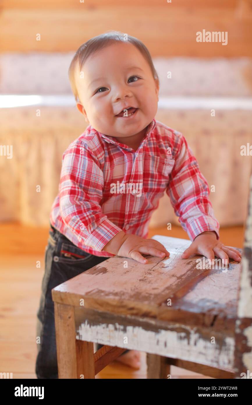 Baby holding on to chair Stock Photo - Alamy