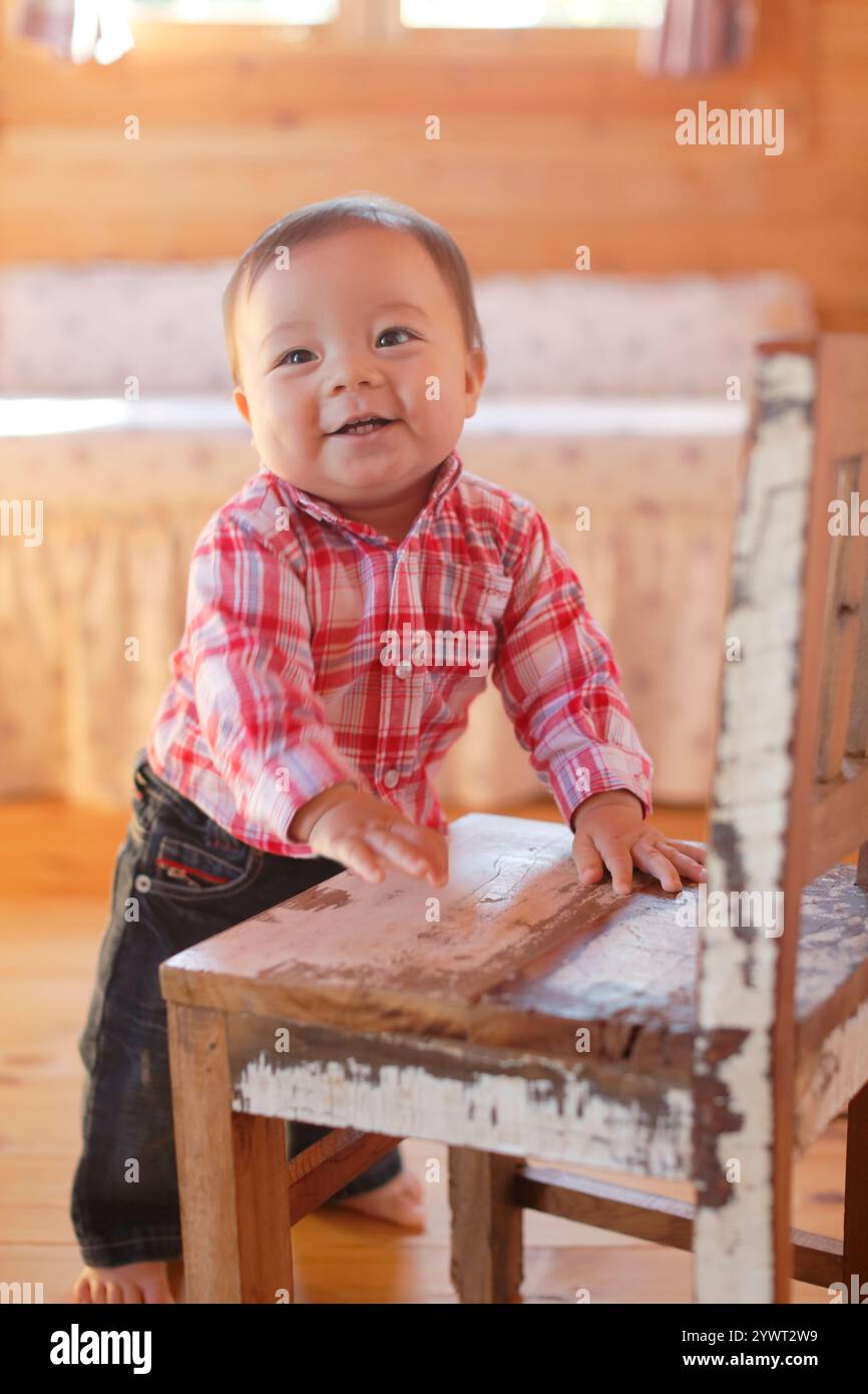 Baby holding on to chair Stock Photo - Alamy