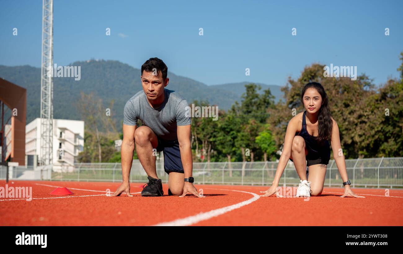 Two determined Asian runners in the starting position, ready to race on ...