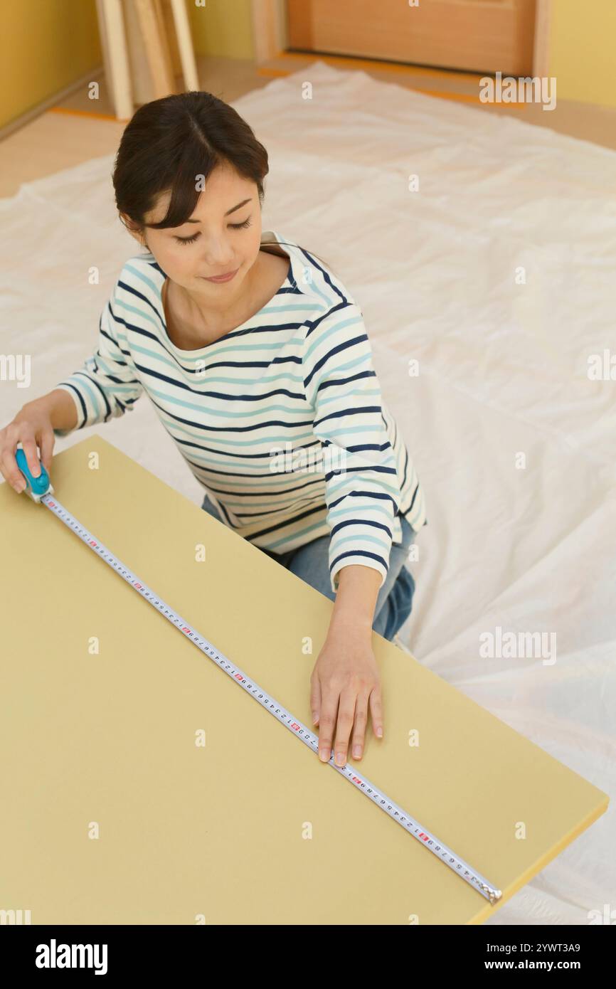 Woman taking measurements of a board with a measuring tape Stock Photo ...