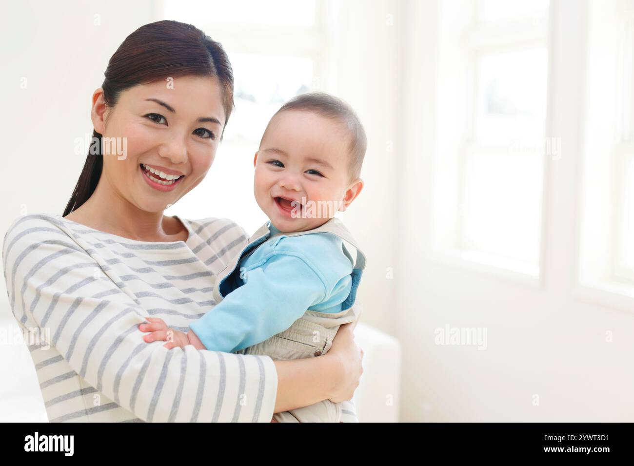 Baby being carried by mother in the living room Stock Photo - Alamy