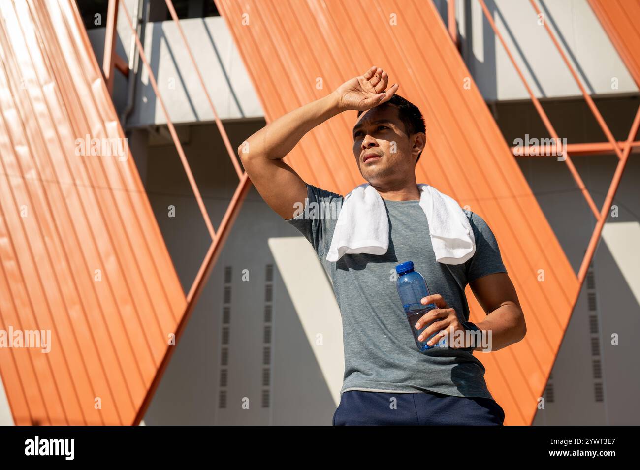 A portrait of a tired, sweaty Asian man in sportswear, exhausted from ...