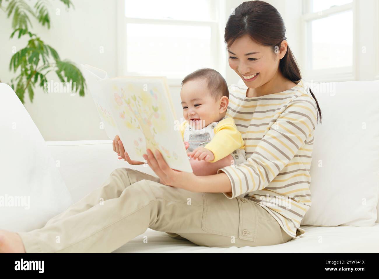 Mother and baby reading picture book on sofa Stock Photo - Alamy