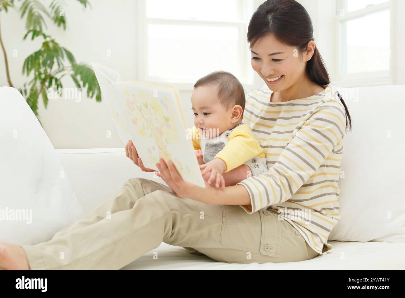 Mother and baby reading picture book on sofa Stock Photo - Alamy