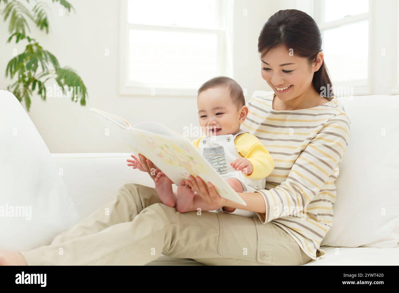 Mother and baby reading picture book on sofa Stock Photo - Alamy