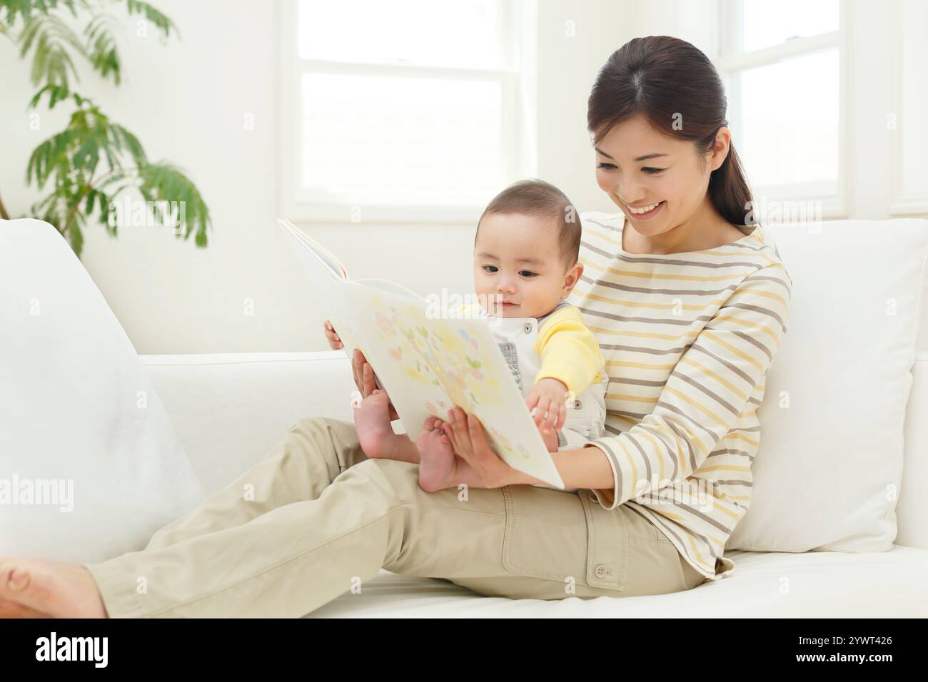 Mother and baby reading picture book on sofa Stock Photo - Alamy