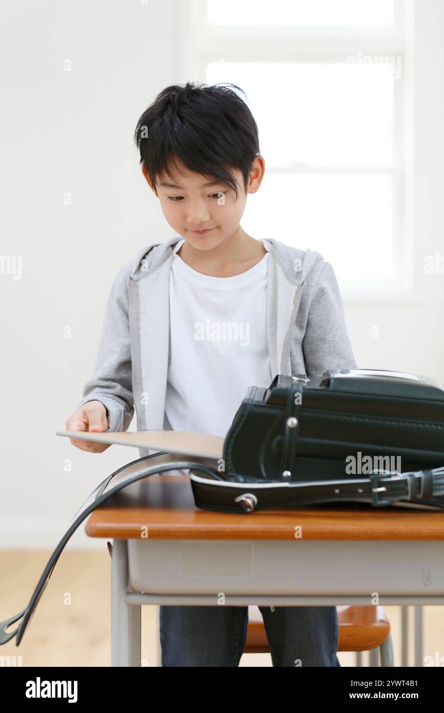 Boy getting ready to leave school in classroom Stock Photo - Alamy