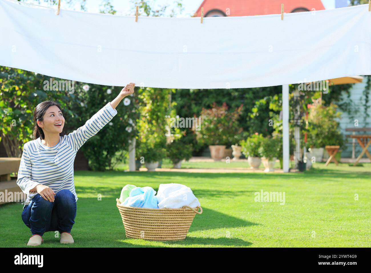 Woman drying clothes in large garden Stock Photo - Alamy