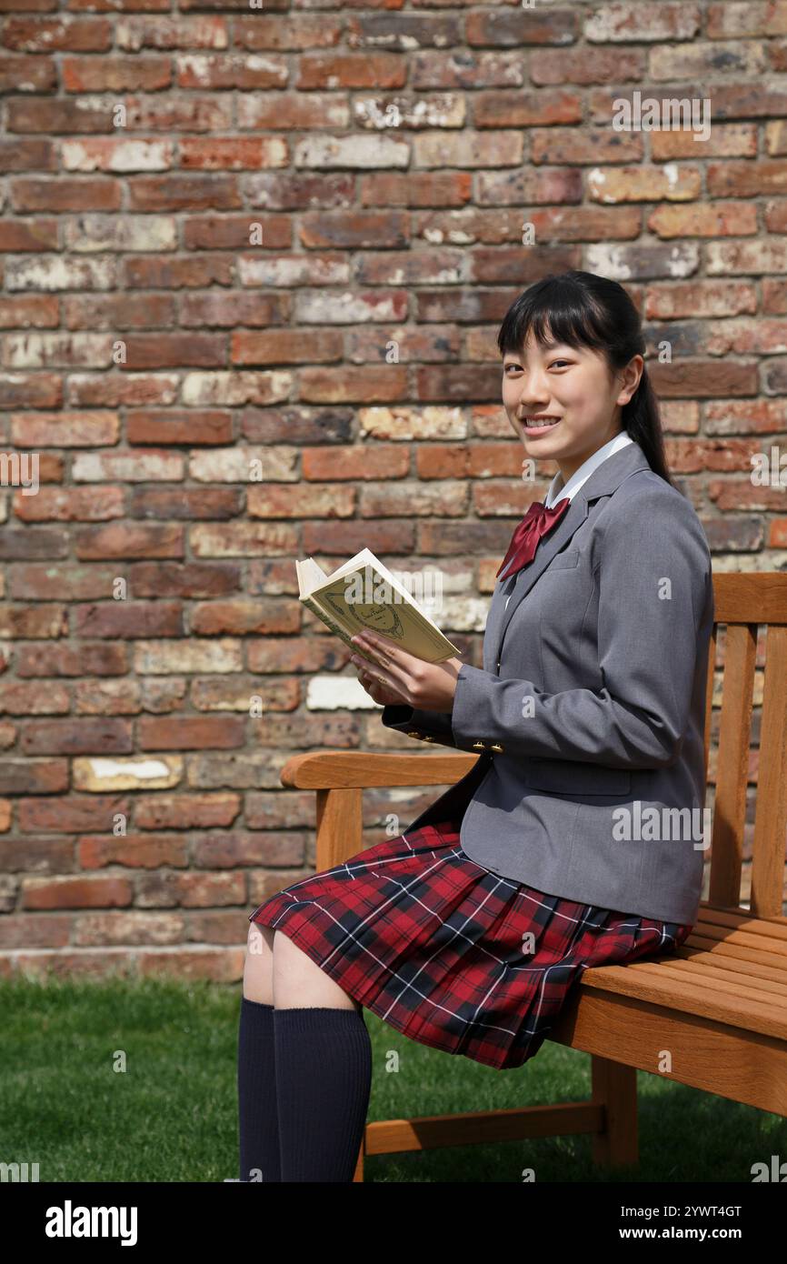 Girl in uniform reading a book on a bench Stock Photo - Alamy