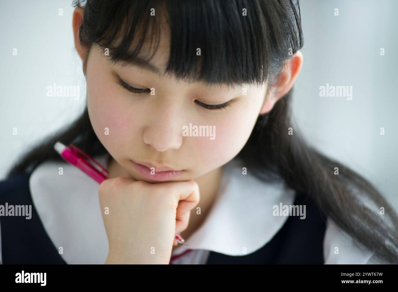 Female student holding a pen and thinking in the classroom Stock Photo ...