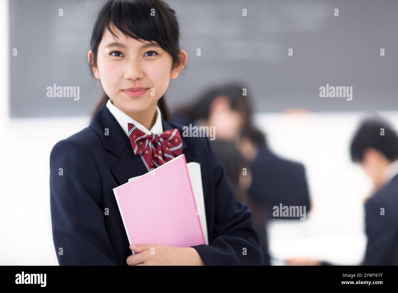 Portrait of smiling female student with teaching materials in classroom ...