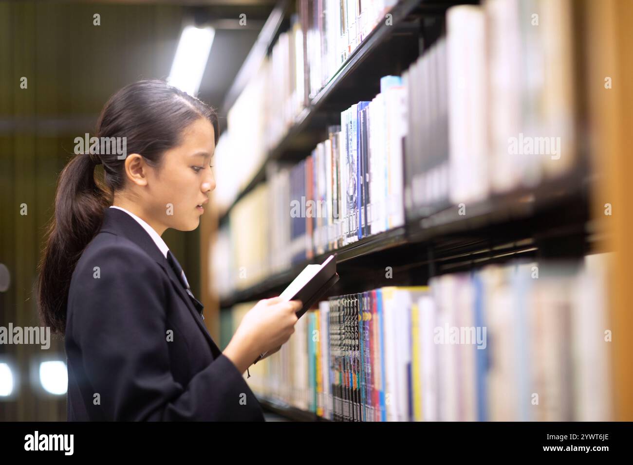 High school girl reading a book in the library Stock Photo - Alamy