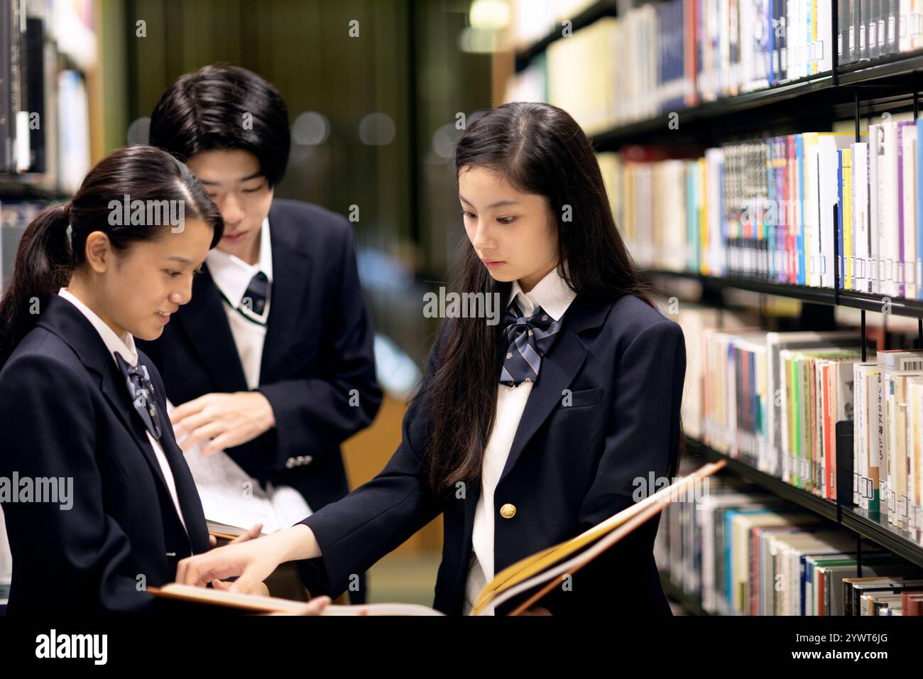 High school student reading a book while standing in the library Stock ...