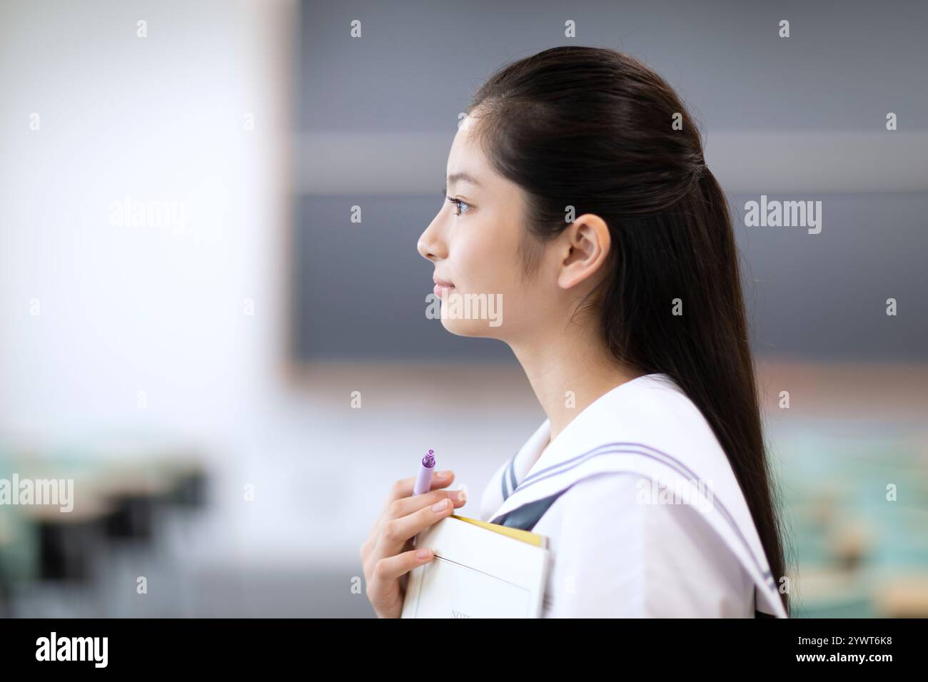 Female high school student standing in classroom in profile Stock Photo ...