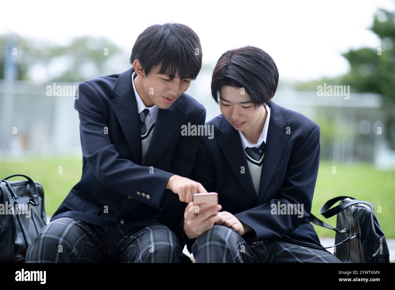 High school boy talking while looking at his smartphone Stock Photo - Alamy