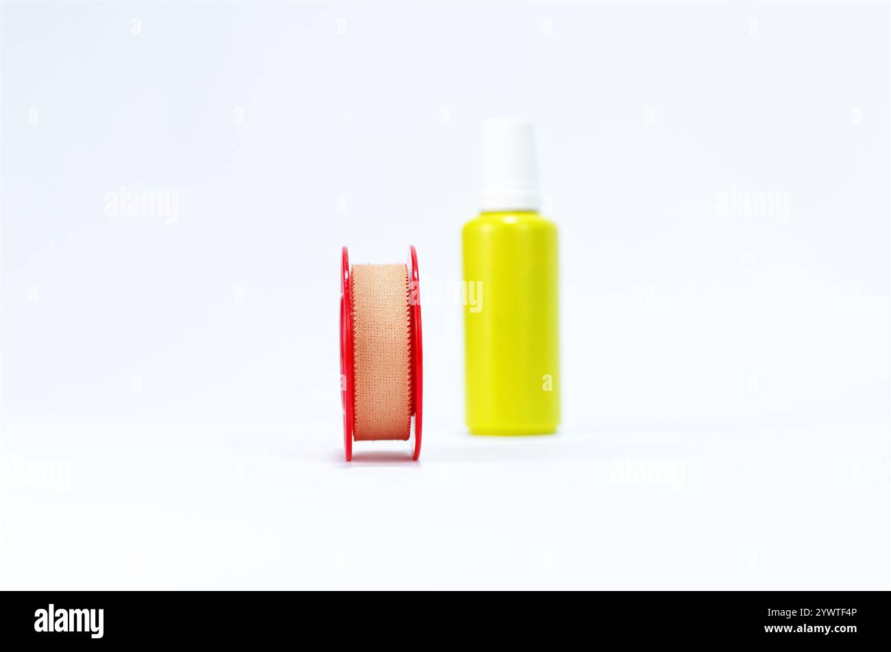 Roll of Adhesive Bandage and Yellow Sanitizer Bottle on White ...