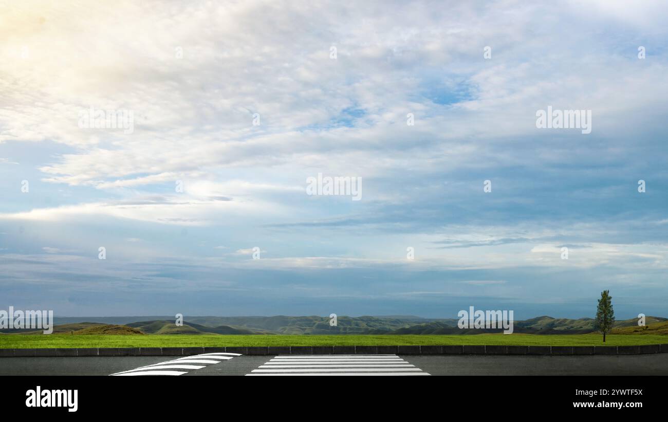 Asphalt street with pedestrian crosswalk and meadow field with blue sky ...