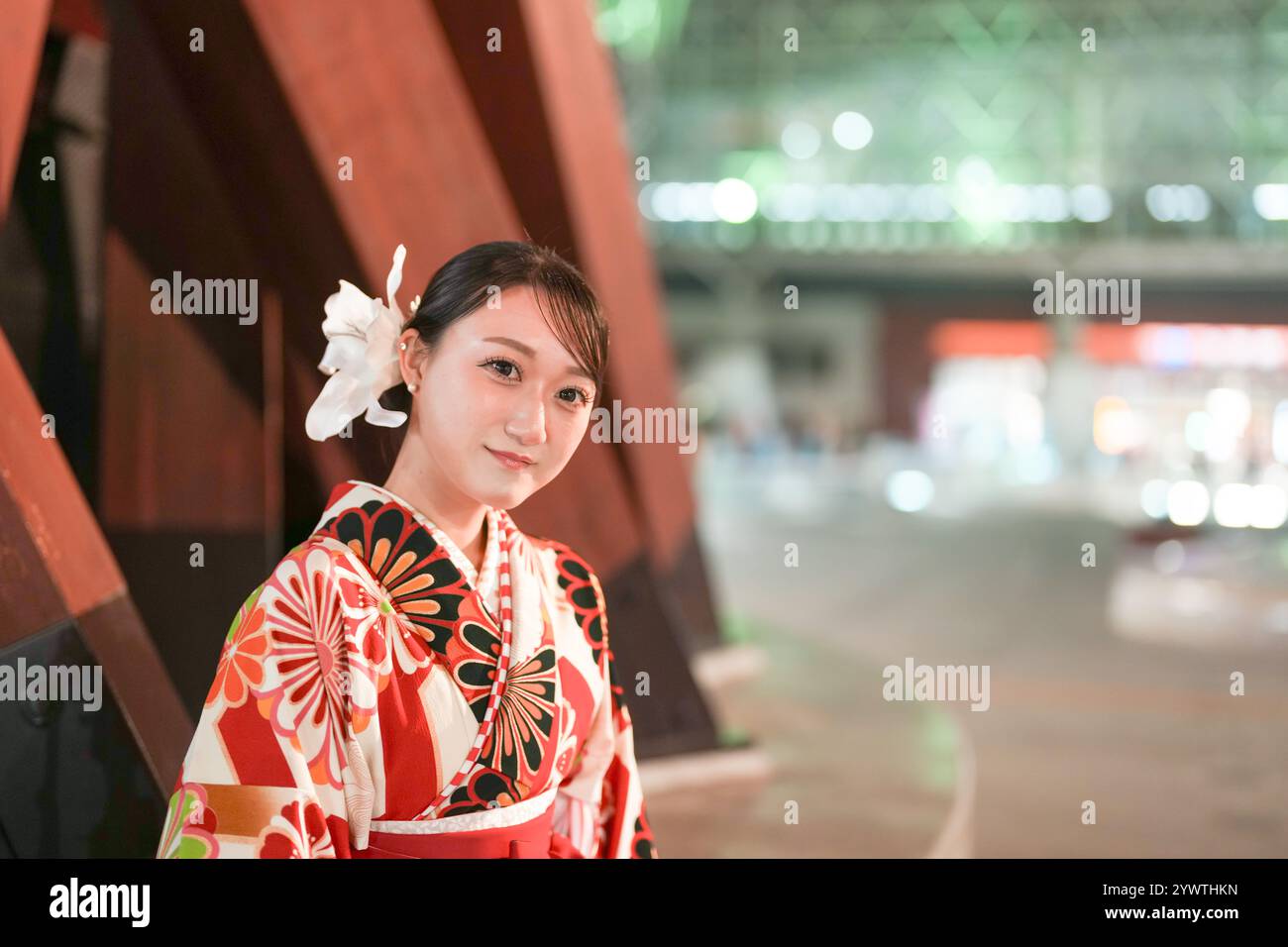 A Japanese woman in her 20s sits at an illuminated train station in ...
