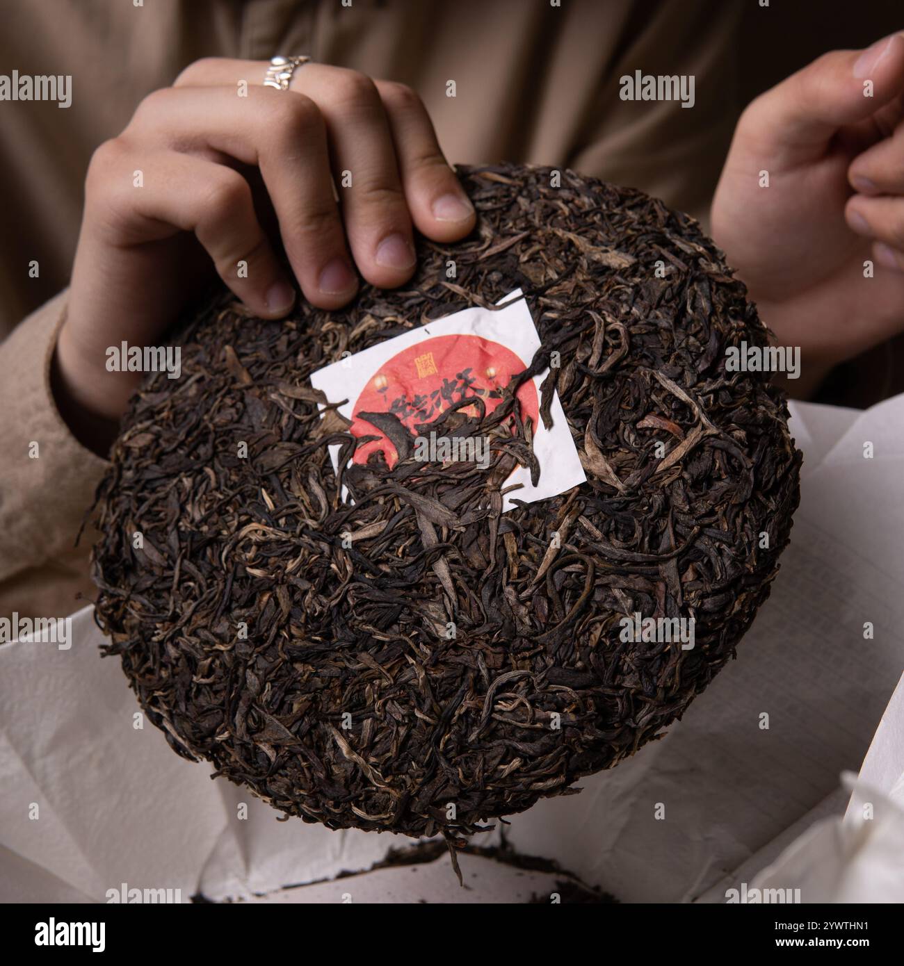 A Hand Holding a Compressed Tea Cake That is Intact Within Its Unique ...