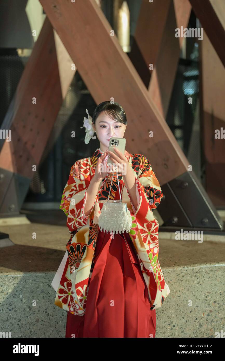 A Japanese woman in her 20s sits at an illuminated train station in ...