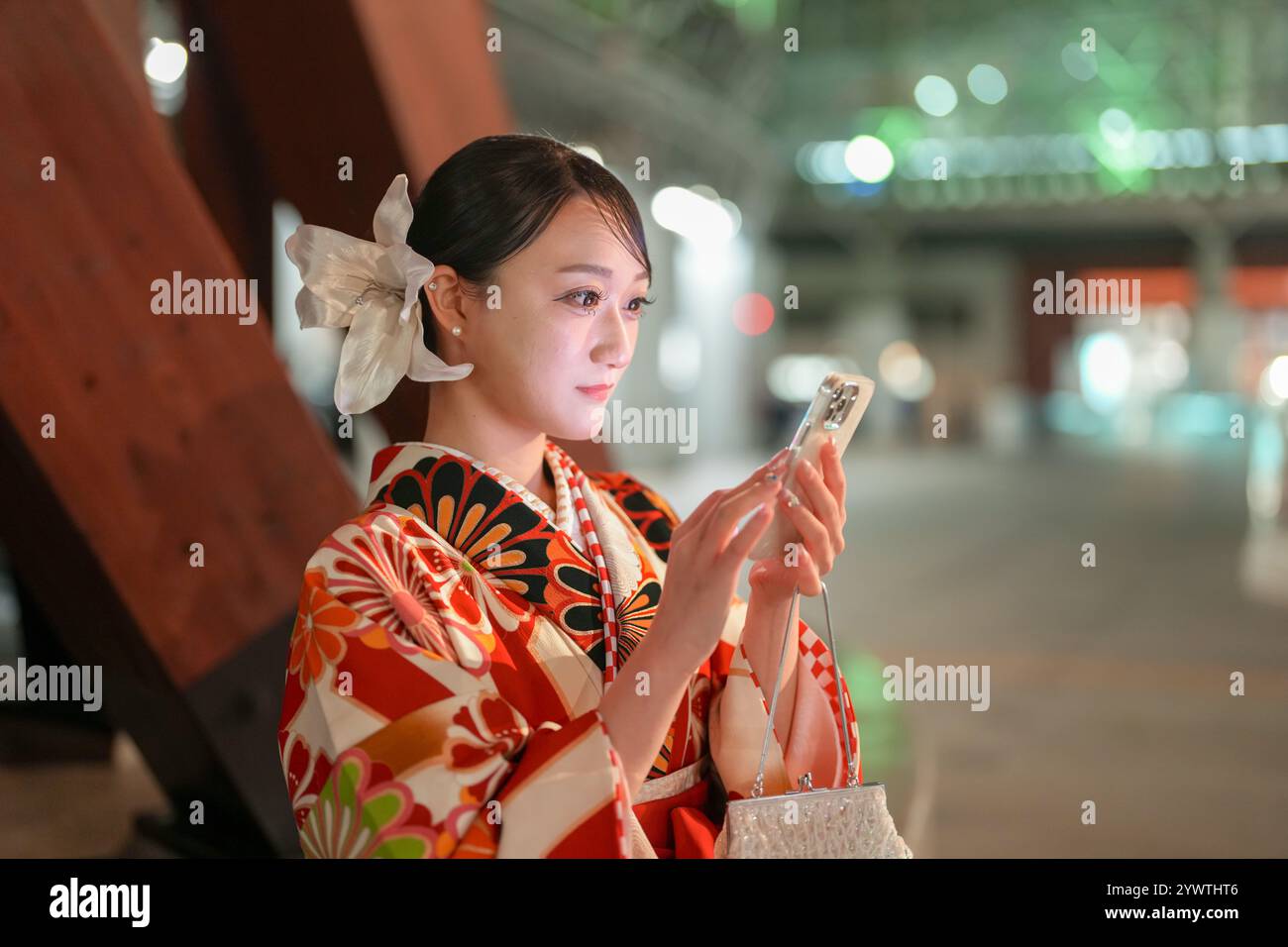 A Japanese woman in her 20s sits at an illuminated train station in ...