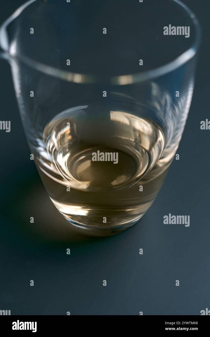 A glass of liquid is elegantly placed on a dark surface, enhancing its ...