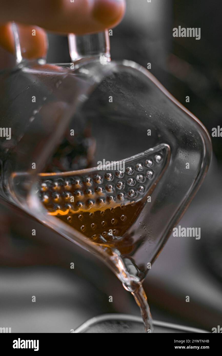 Pouring a rich liquid through a strainer into a beautifully designed ...
