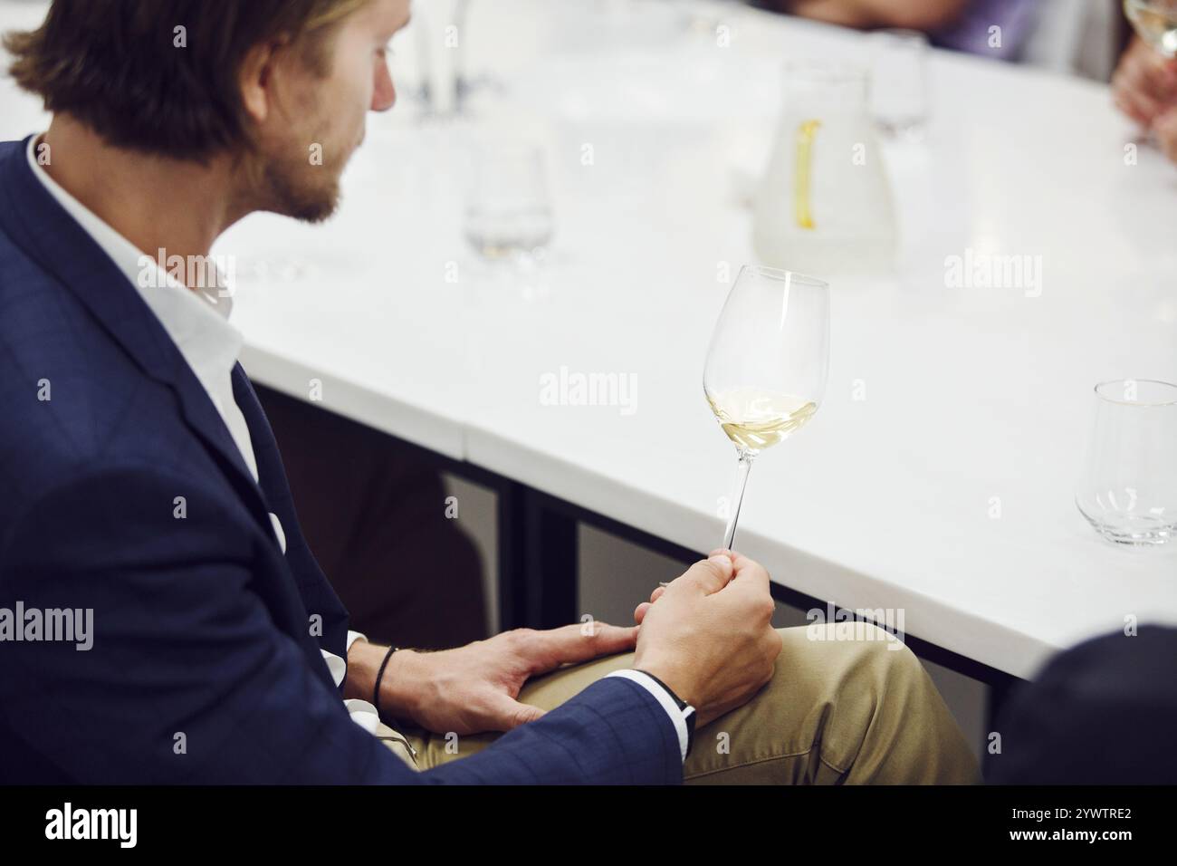 Attractive and mature looking male sommelier tests white wine in a ...