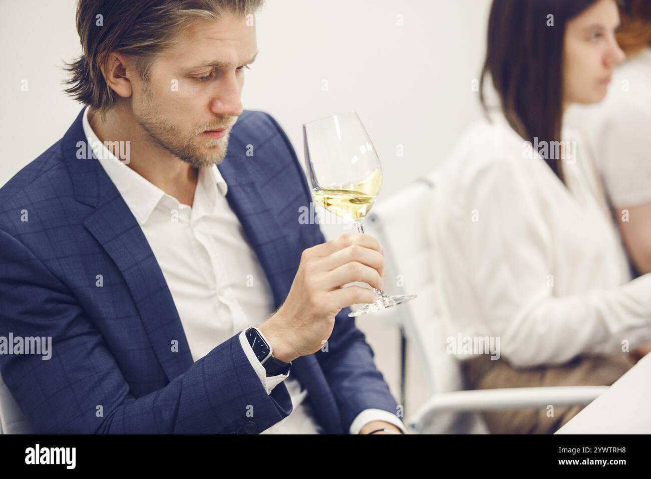 Adult male sommelier smelling and tasting white wine into glass during ...
